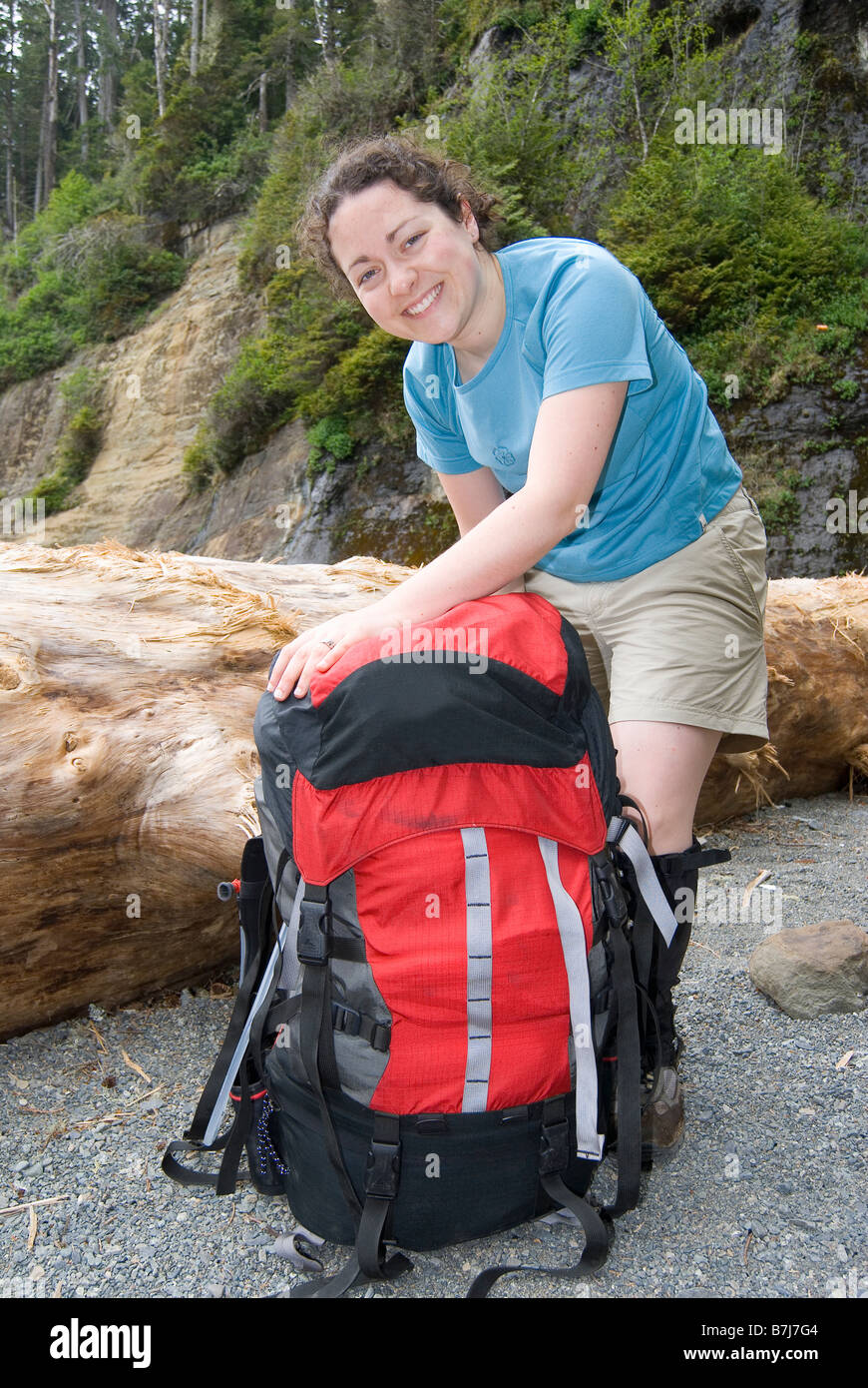 Woman (20-25) packing a large backpack on a beach , West Coast Trail ...