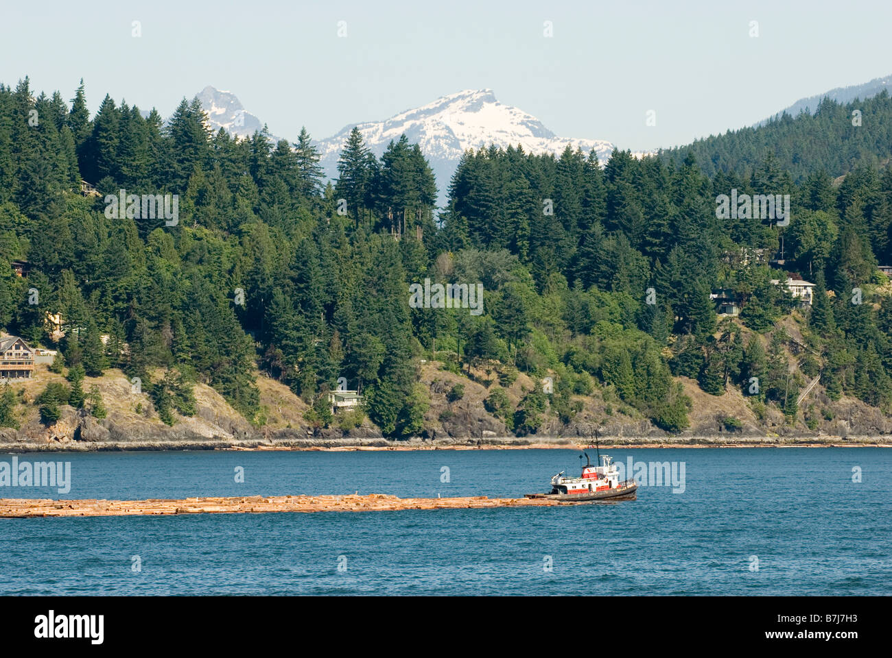 Tug Boat pulling logs through the ocean with mountains in the ...