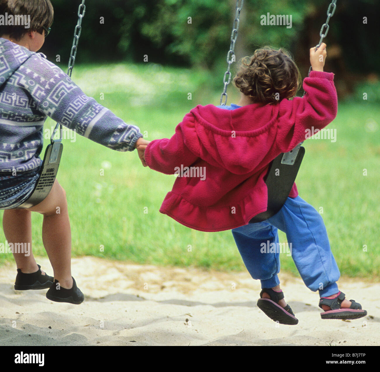Kids hold hands while playing on swing, Hornby Island, BC Canada Stock ...