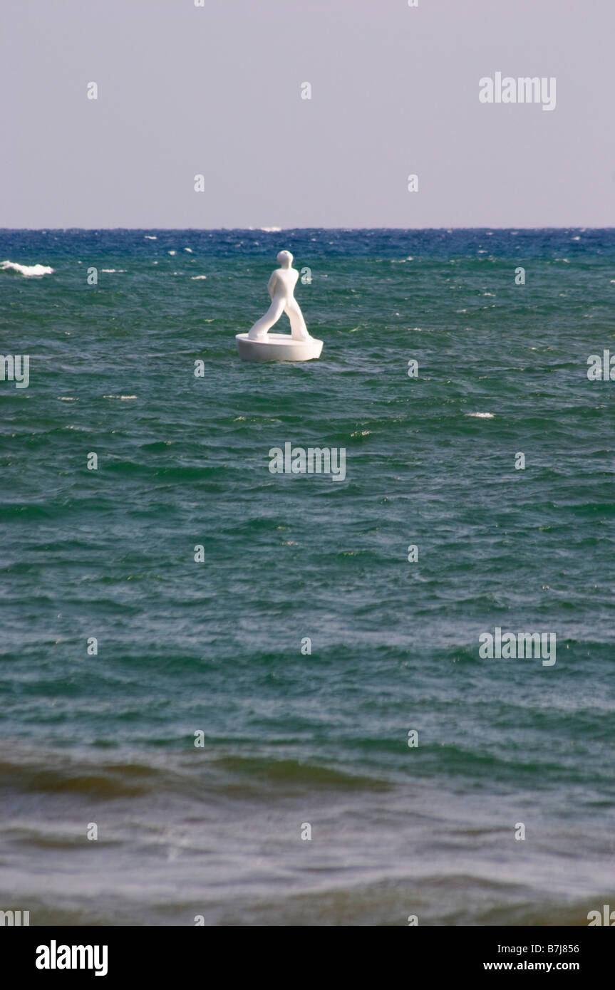 A white sculpture of a man floating like a buoy in the sea. Sitges ...
