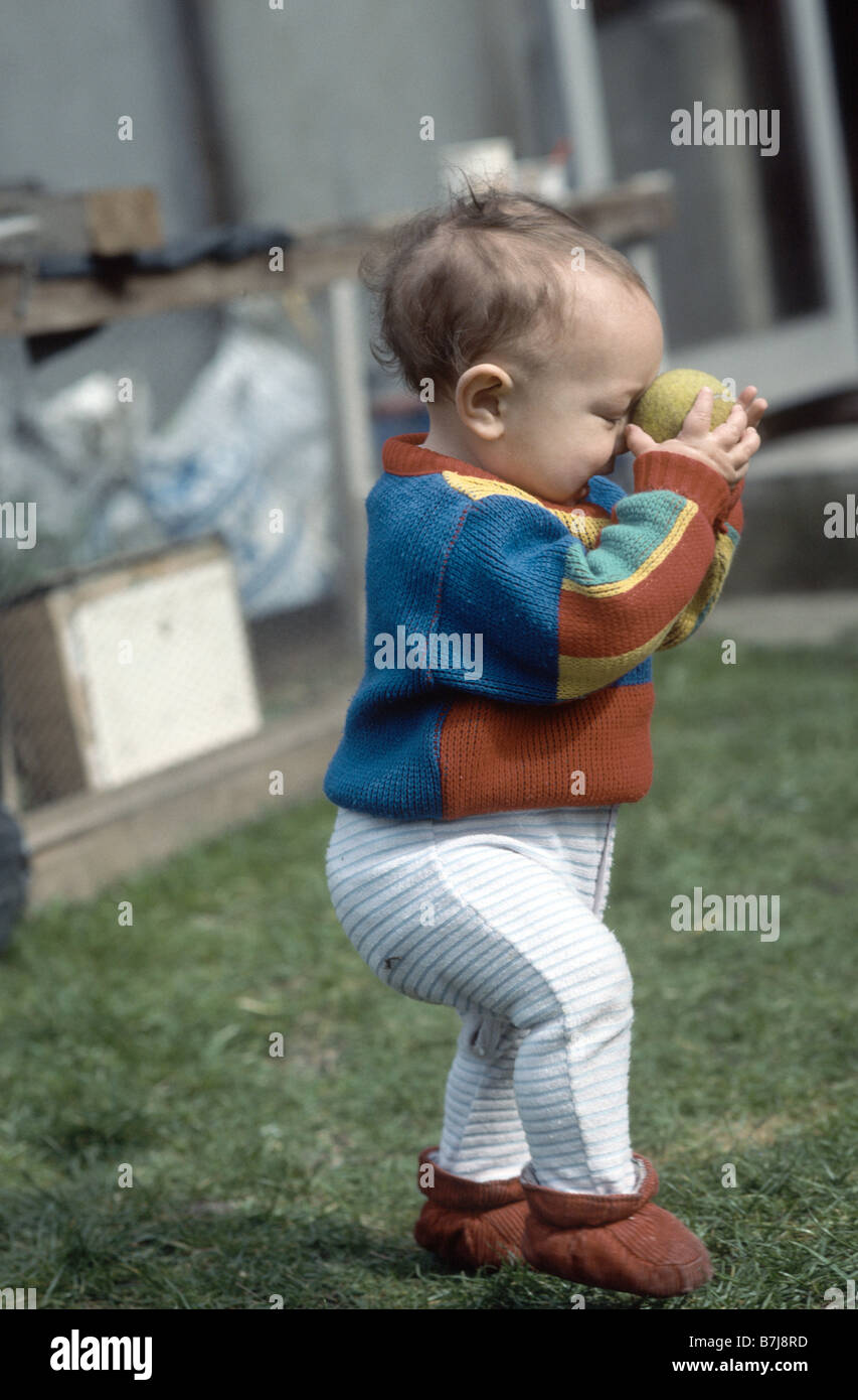 baby exploring first steps and holding a ball Stock Photo - Alamy