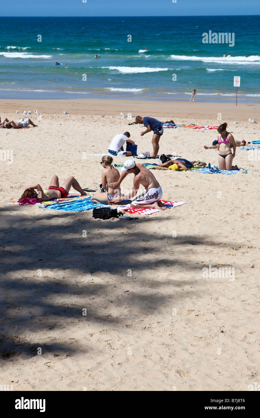 Man rubbing sunscreen on woman's back Stock Photo - Alamy