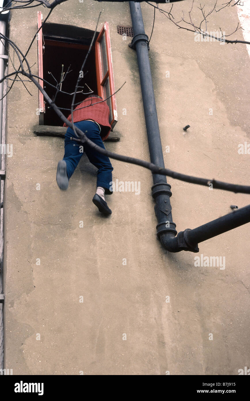 A boy breaking into a house by crawling into an open window Stock Photo ...