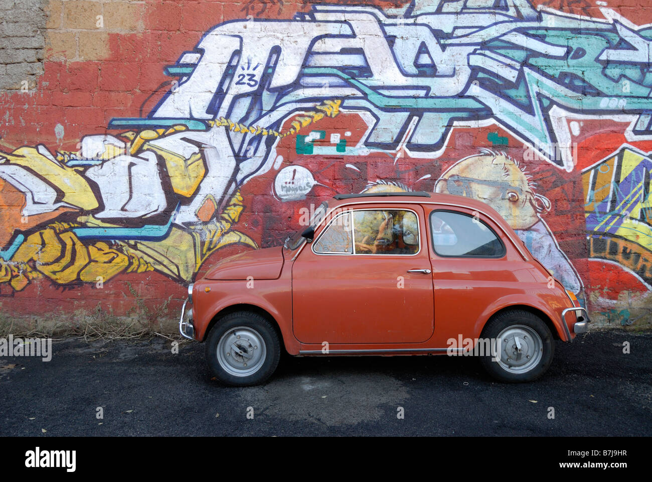 iconic italian small red Fiat 500 car against contemporary graffiti ...