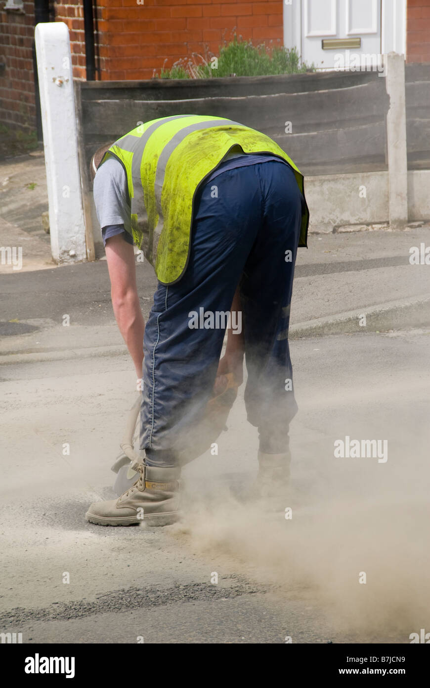 Workman using an industrial masonry cutter in a suburban street ...
