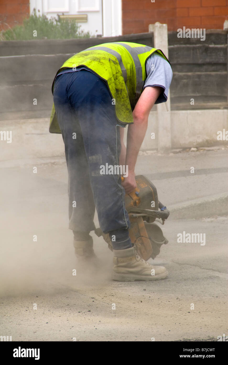 Workman using an industrial masonry cutter in a suburban street ...