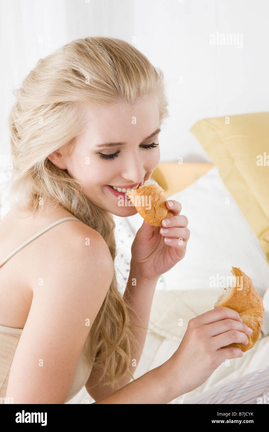 Woman eating croissant in bed Stock Photo - Alamy