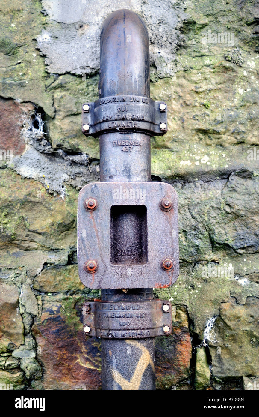 Metal pipe coming out of a stone wall Stock Photo - Alamy