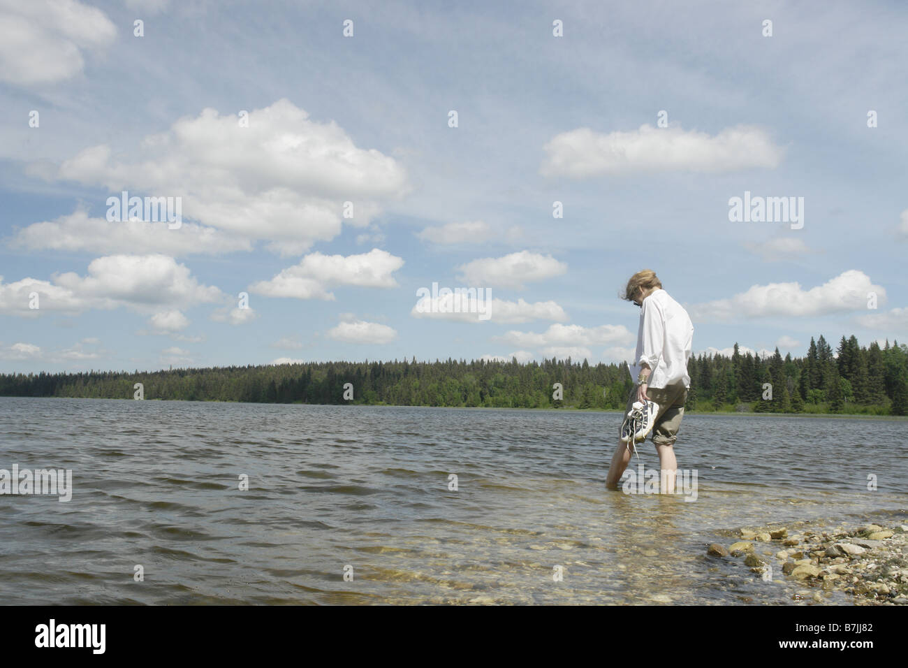 Woman wading in Clear Lake; Canada, Manitoba, Riding Mountain National ...