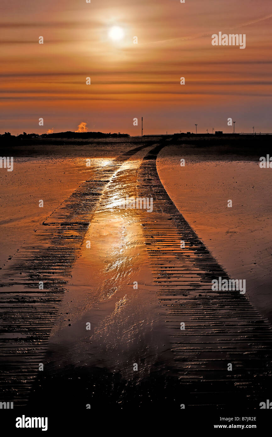 Tracks on beach leading into the sunset Stock Photo - Alamy