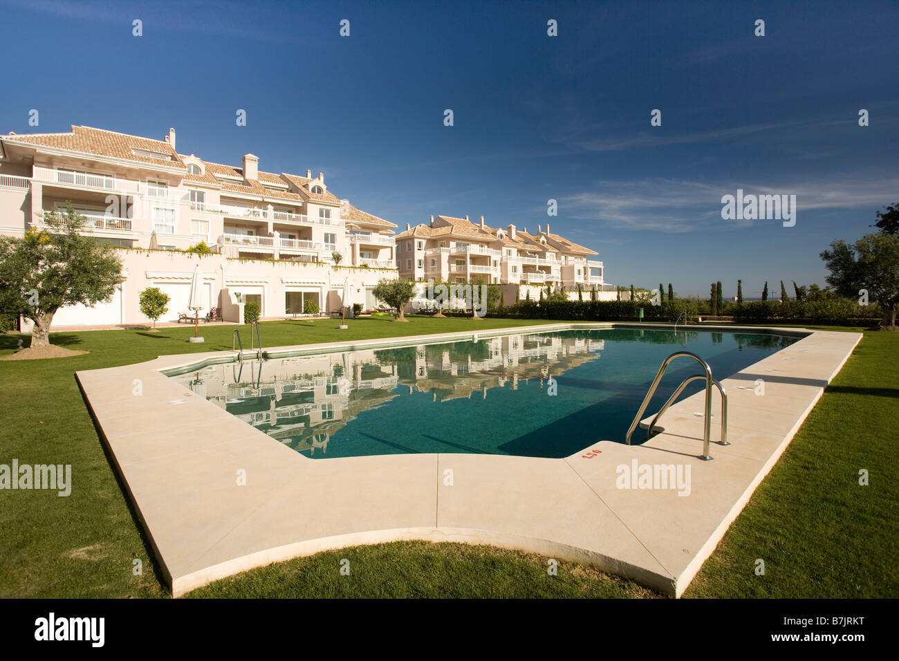 Communal swimming pool with concrete paving situated in gardens in ...