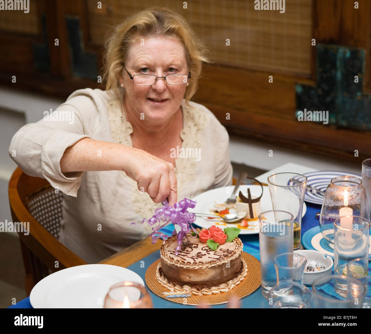 Mature woman cutting birthday cake hi-res stock photography and images ...
