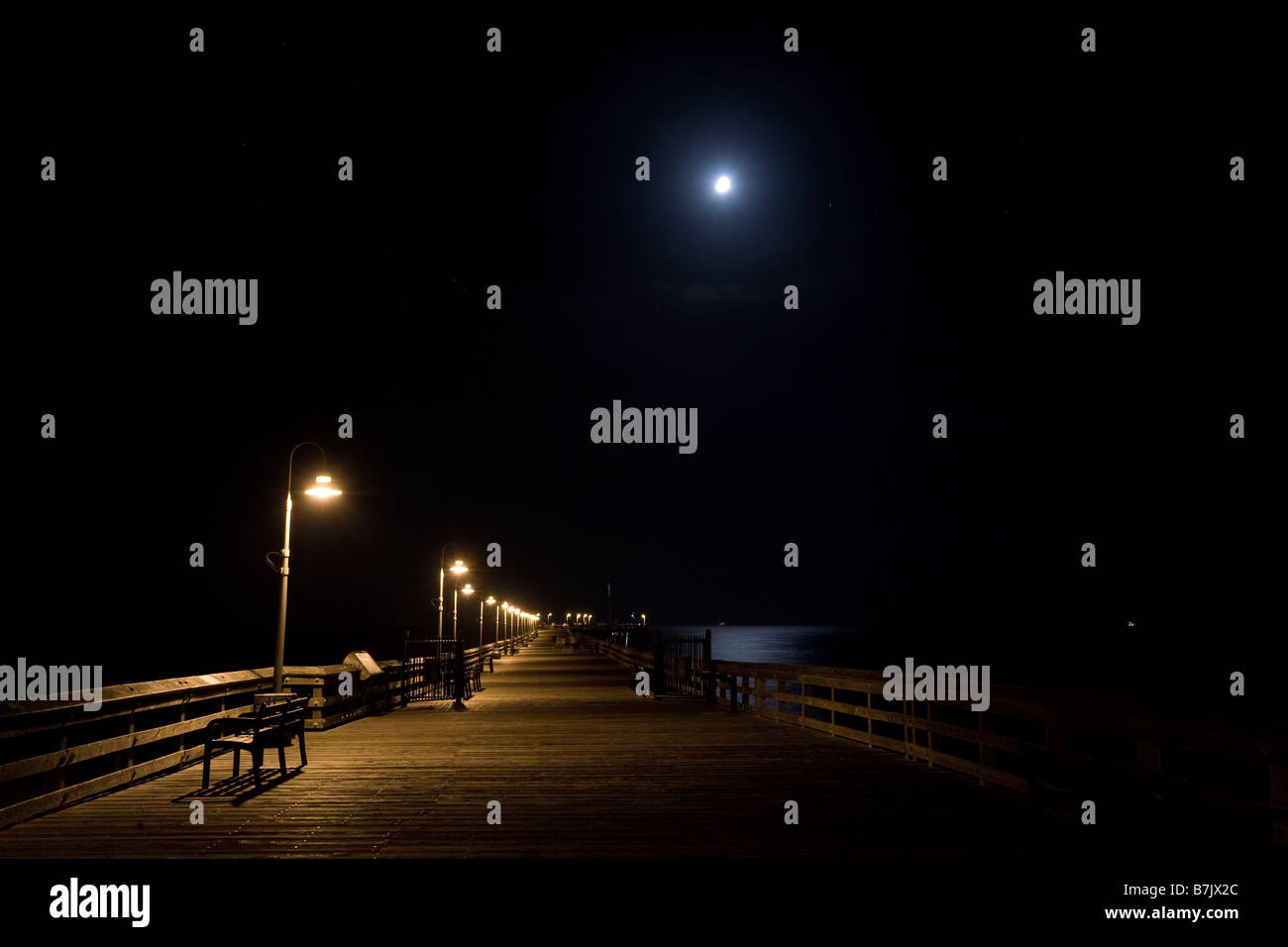 A pier at night with a full moon Stock Photo - Alamy
