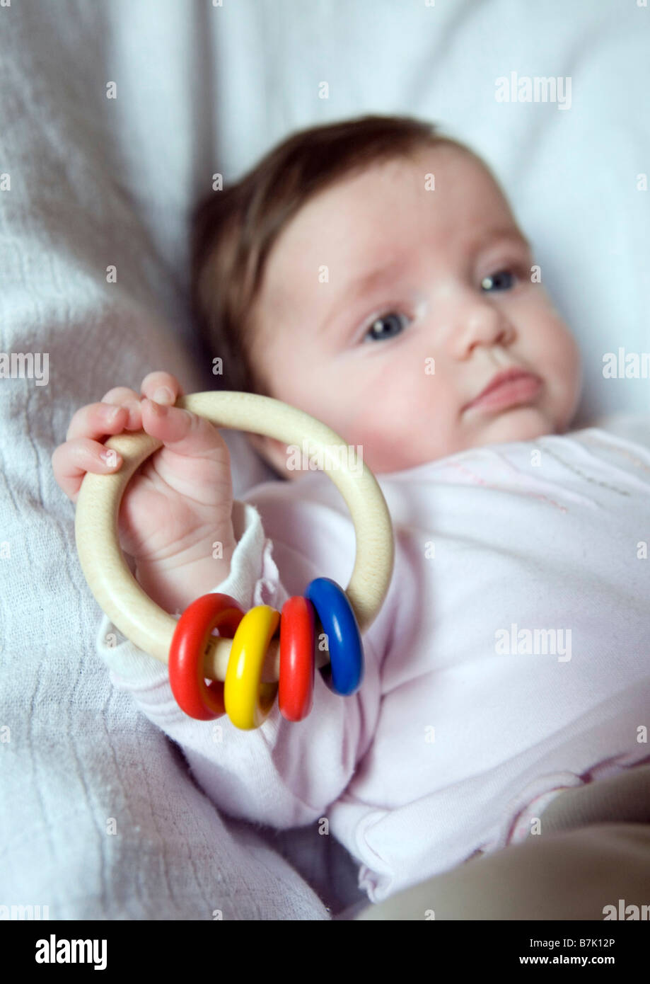 Baby holding a rattle at 14 weeks old Stock Photo - Alamy