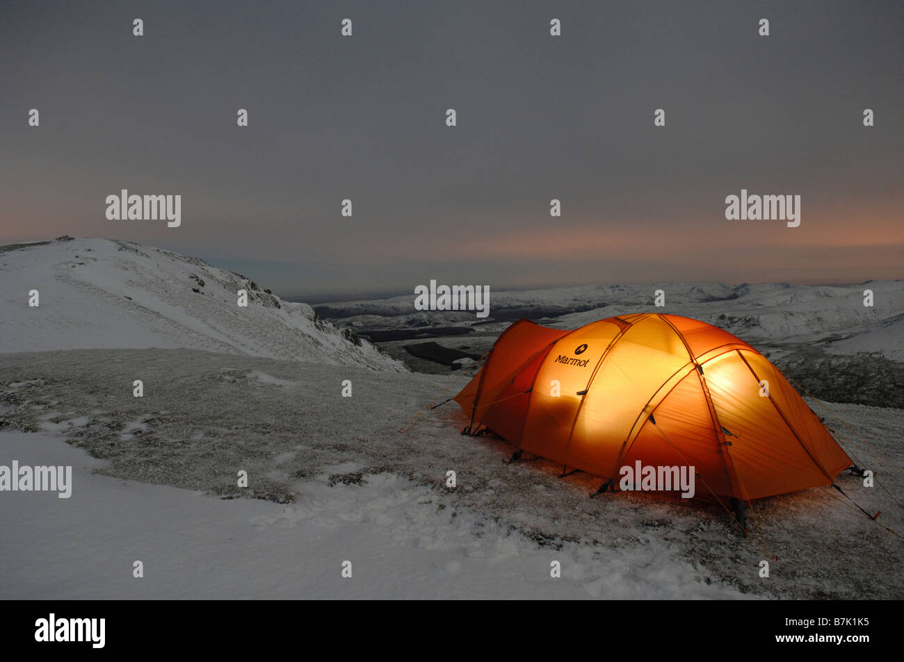 A night scene with a tent glowing while winter camping on Blencathra ...