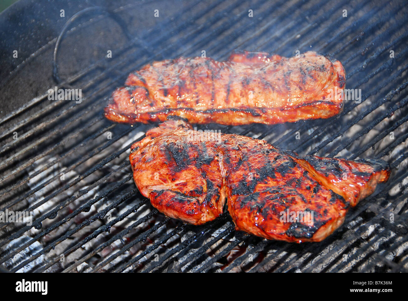 Juicy steaks cooking on a barbeque Stock Photo - Alamy