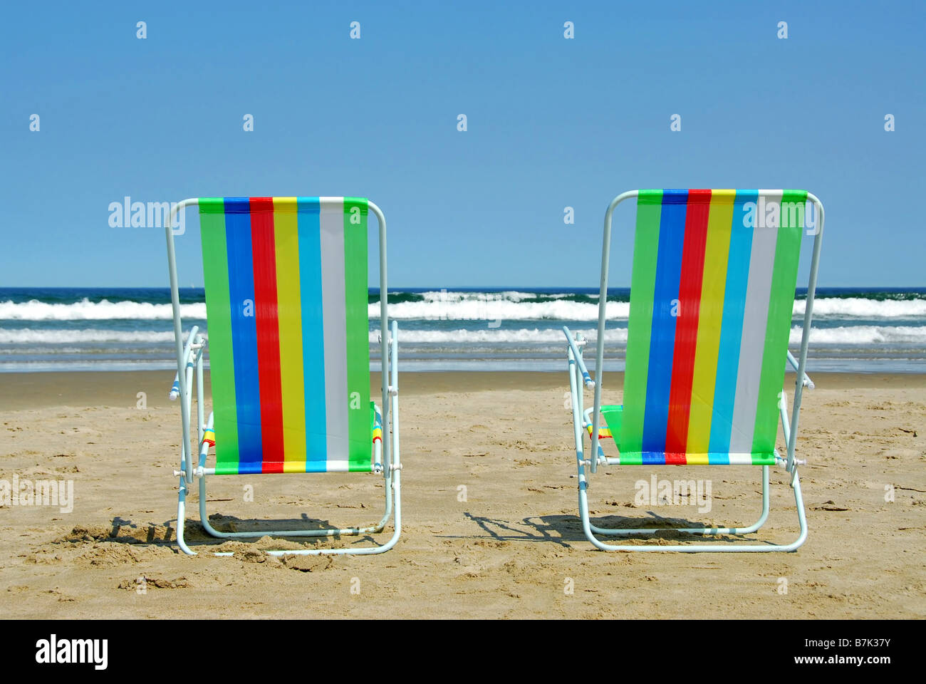 Two colorful beach chairs on the ocean shore Stock Photo - Alamy
