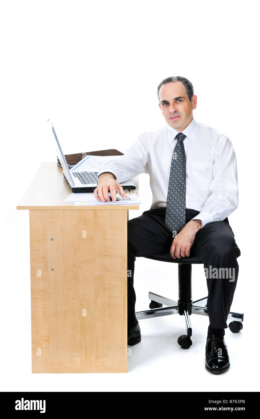 Serious businessman sitting at his desk isolated on white background ...