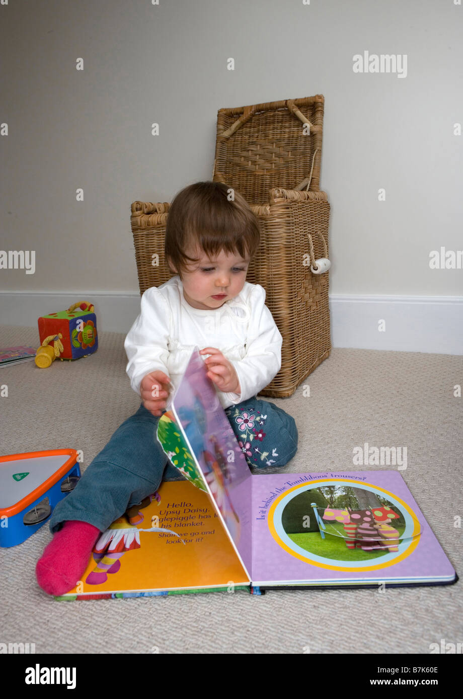 A baby girl looks at a book Stock Photo - Alamy