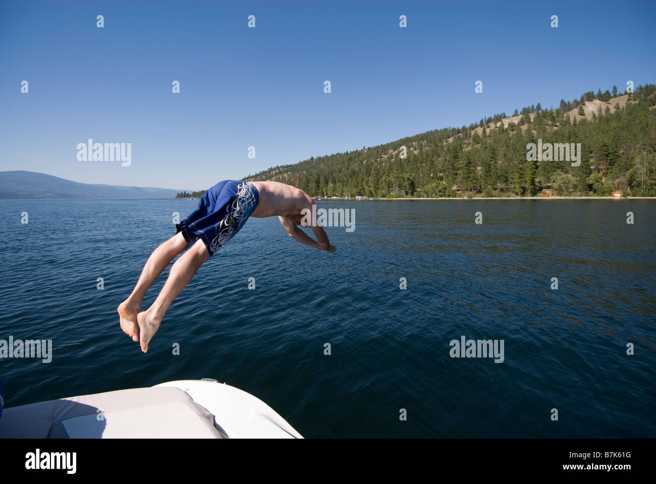 Youth diving off back of four-stroke engine boat, Okanagan Centre, BC ...