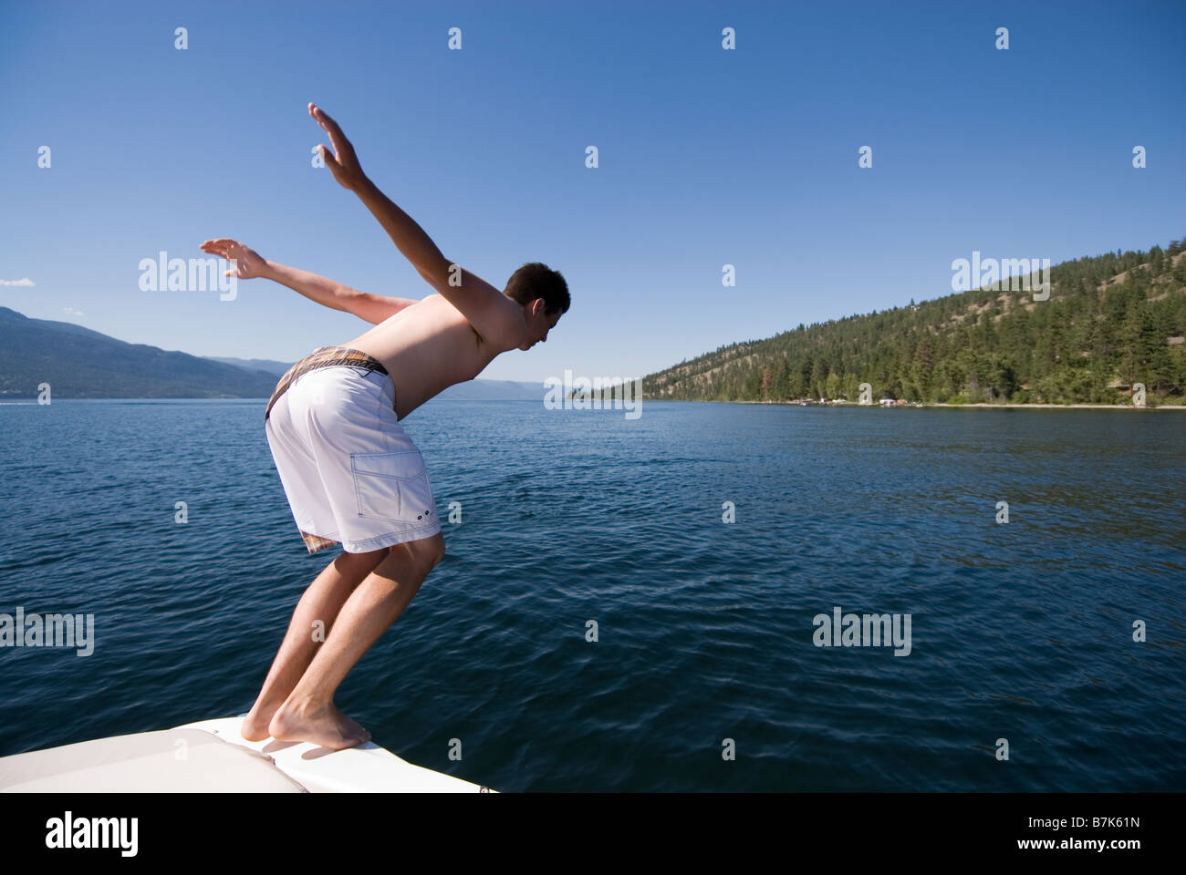 Youth diving off back of fur-stroke engine boat, Okanagan Centre, BC ...