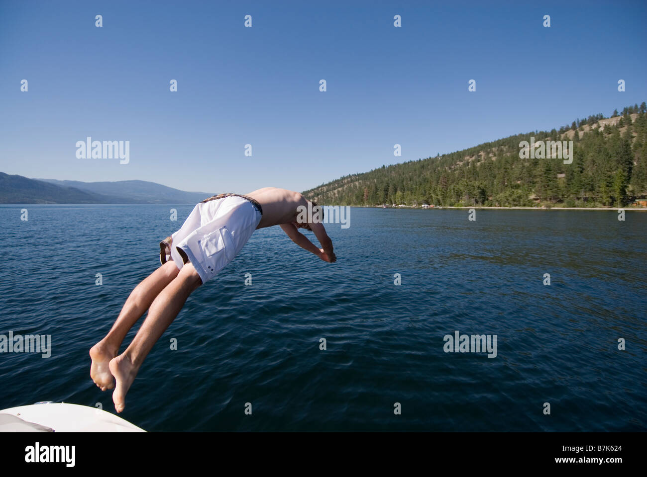 Youth diving off back of four-stroke engine boat, Okanagan Centre, BC ...