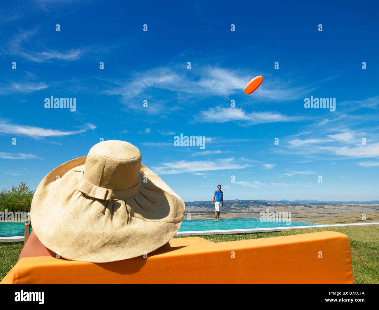 Man throwing Frisbee over pool Stock Photo - Alamy