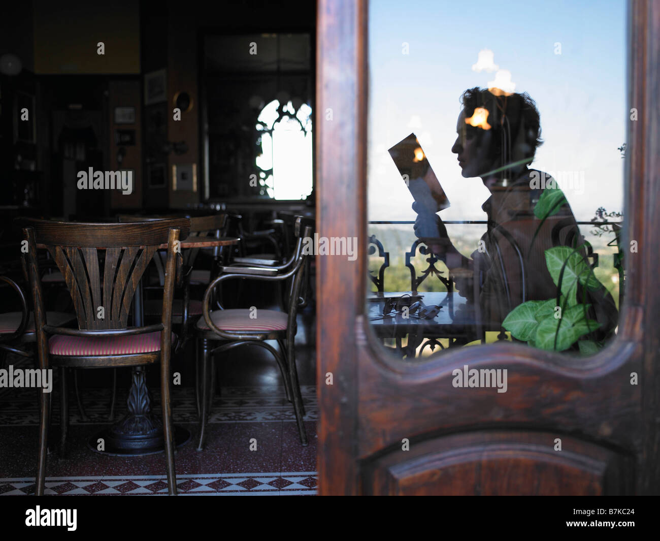 Reflection of man reading in café Stock Photo - Alamy