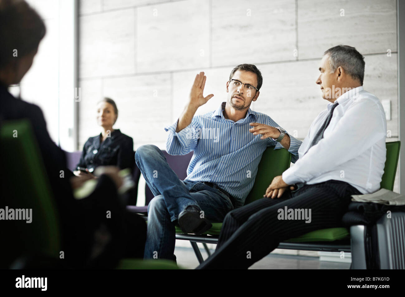 Men talking in waiting room Stock Photo - Alamy