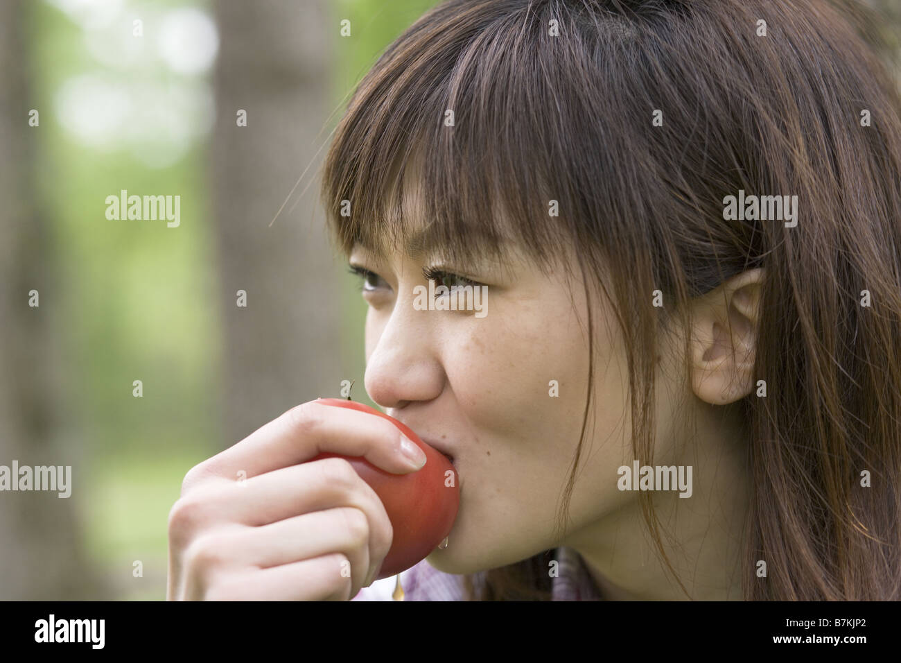 Woman Eating a Tomato Stock Photo - Alamy