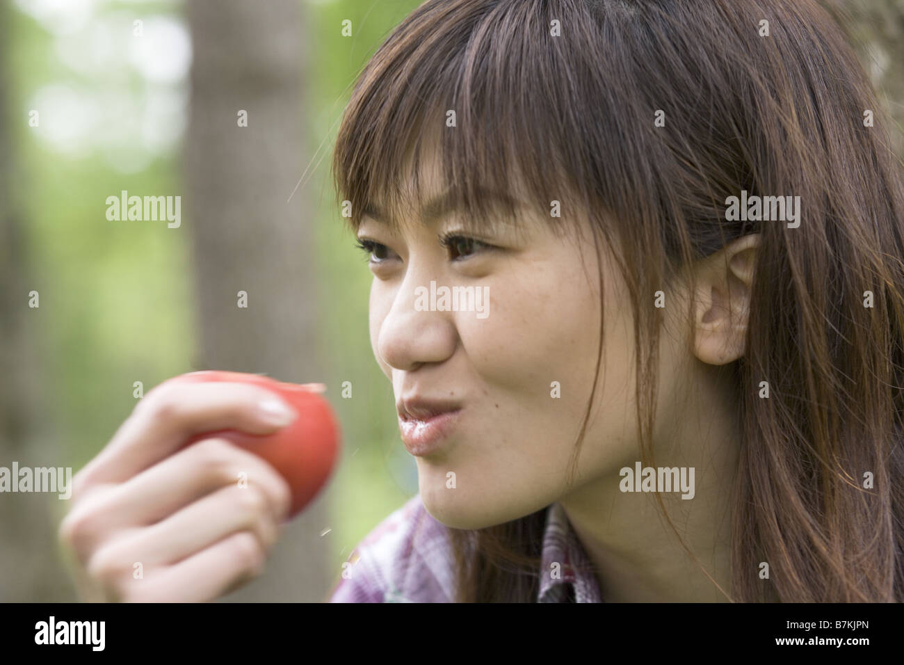 Woman Eating a Tomato Stock Photo - Alamy