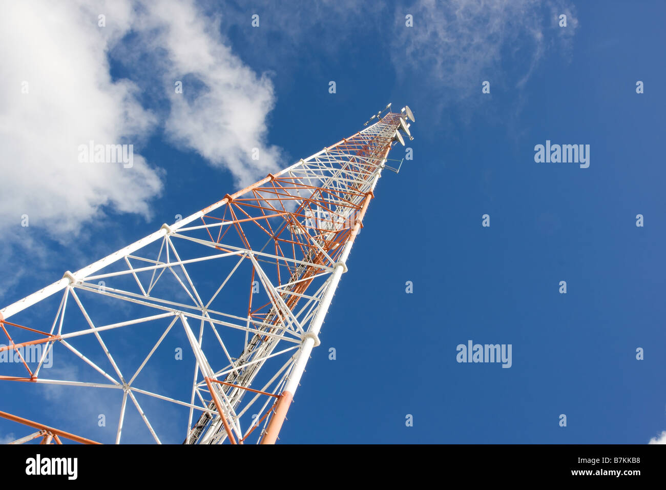 red and white latticed communications mast with blue sky background ...