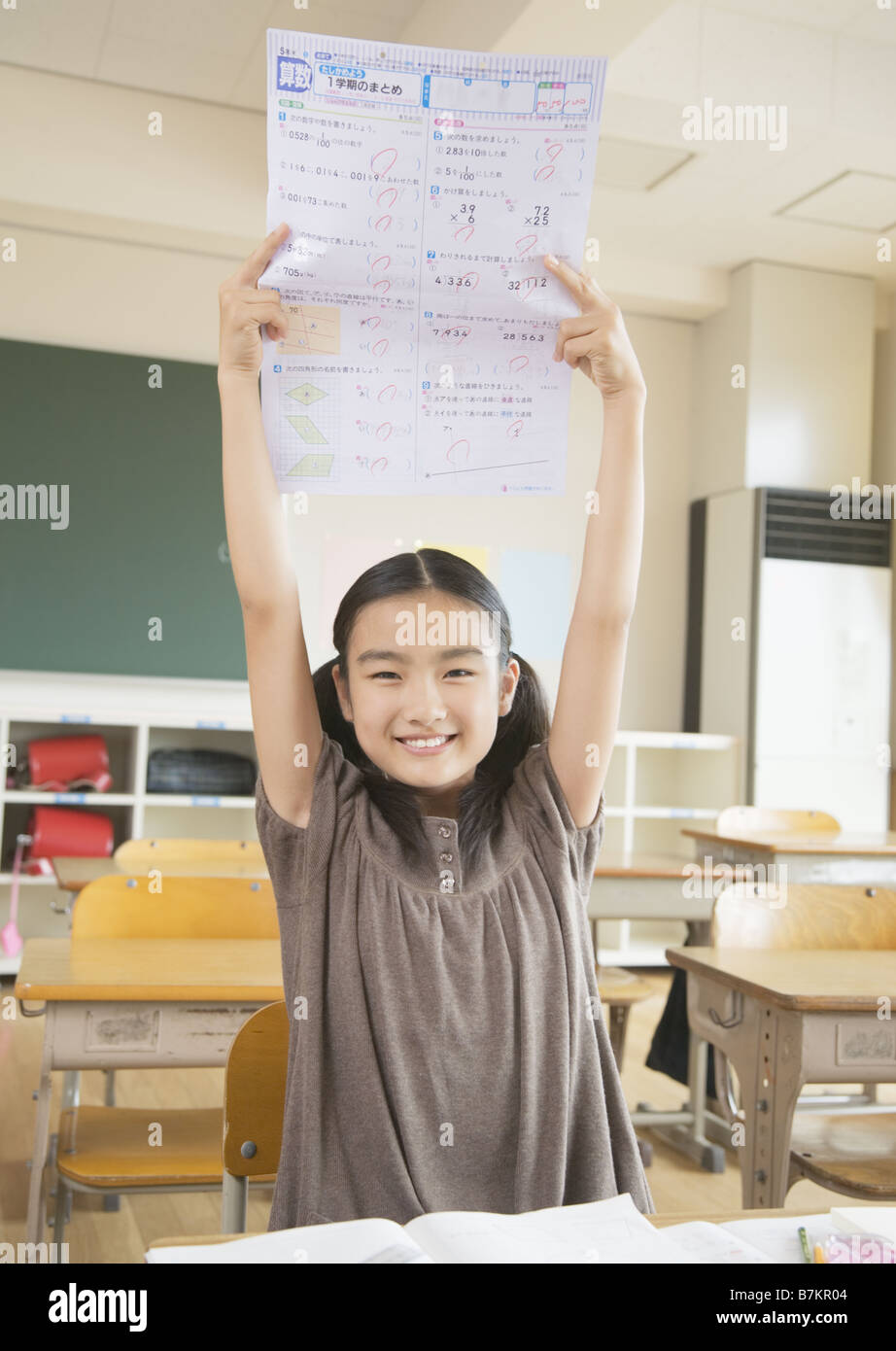 Elementary school girl showing test paper Stock Photo - Alamy