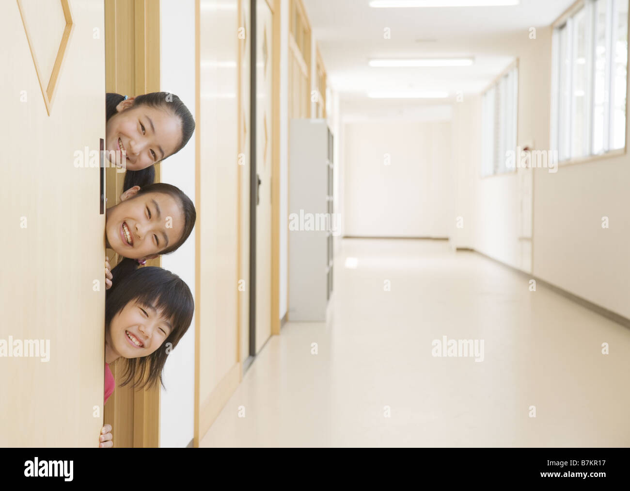 Elementary school students peeking through the door Stock Photo - Alamy