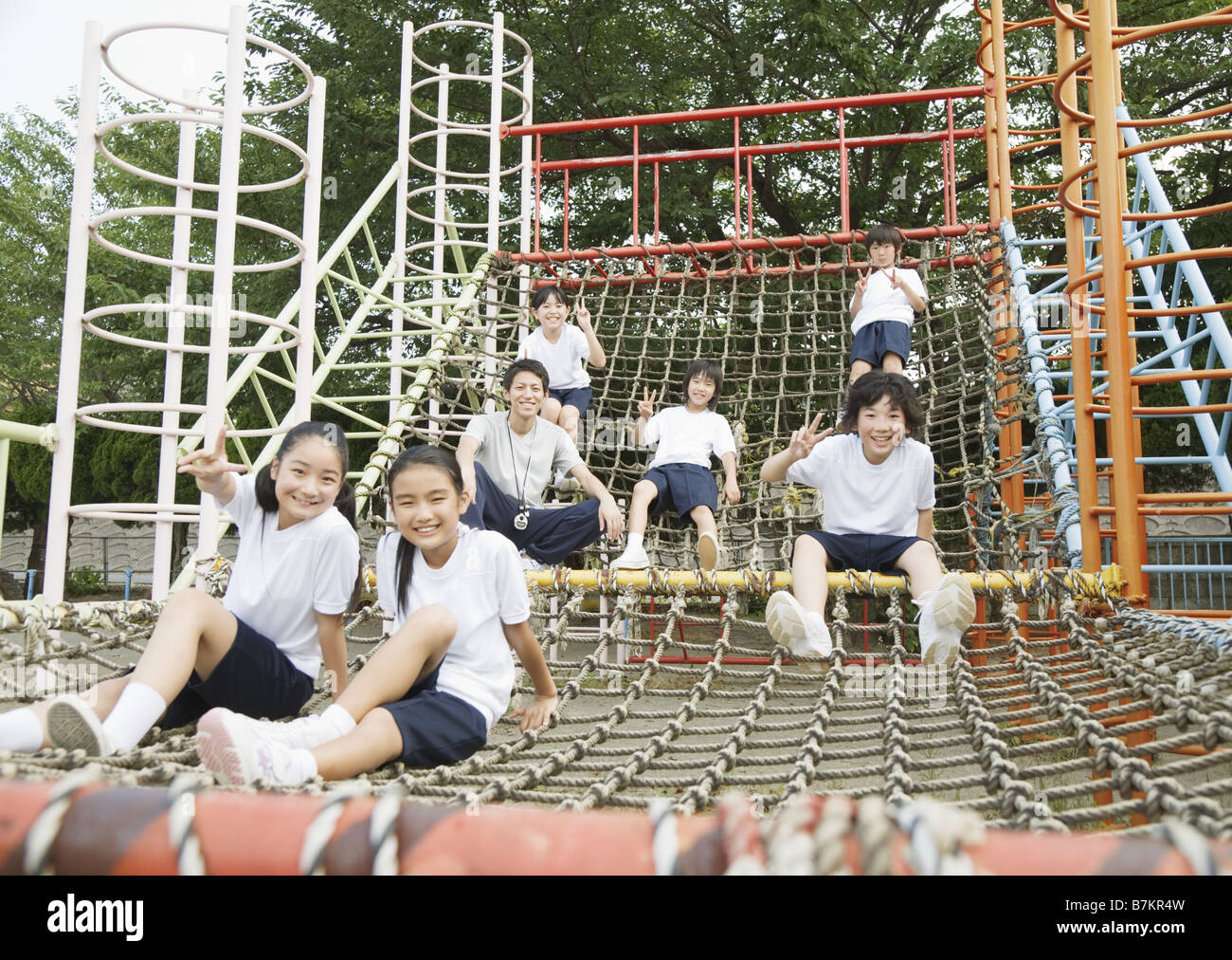Elementary students and teacher sitting on play equipment Stock Photo ...