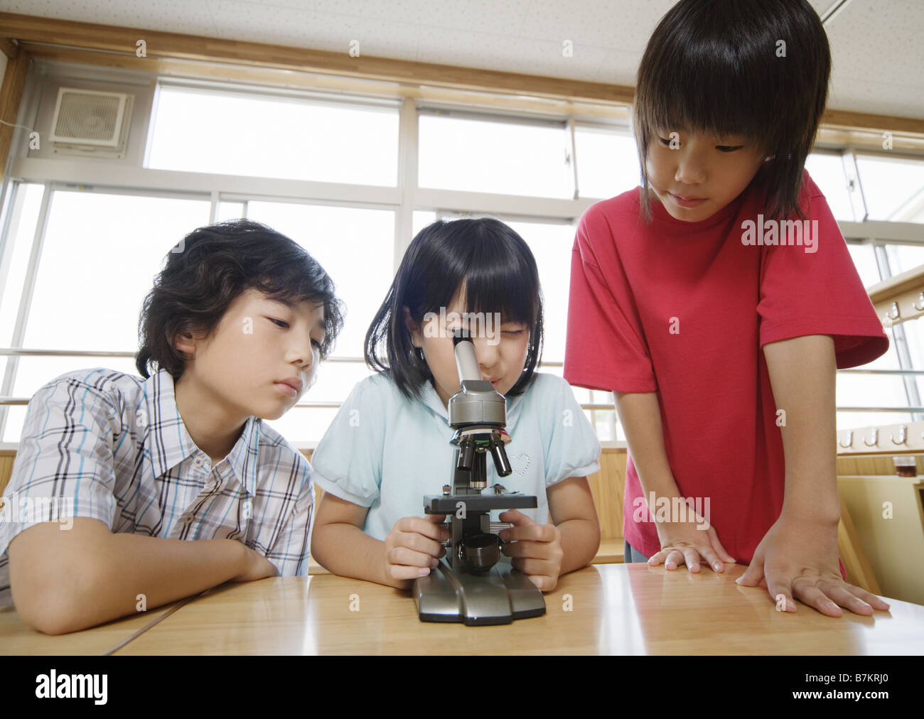 Elementary school student looking through a microscope Stock Photo - Alamy