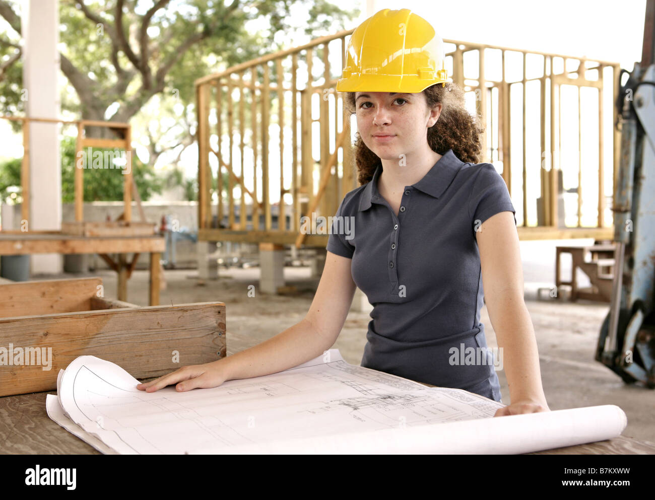 A young female engineering student examining blueprints on a ...