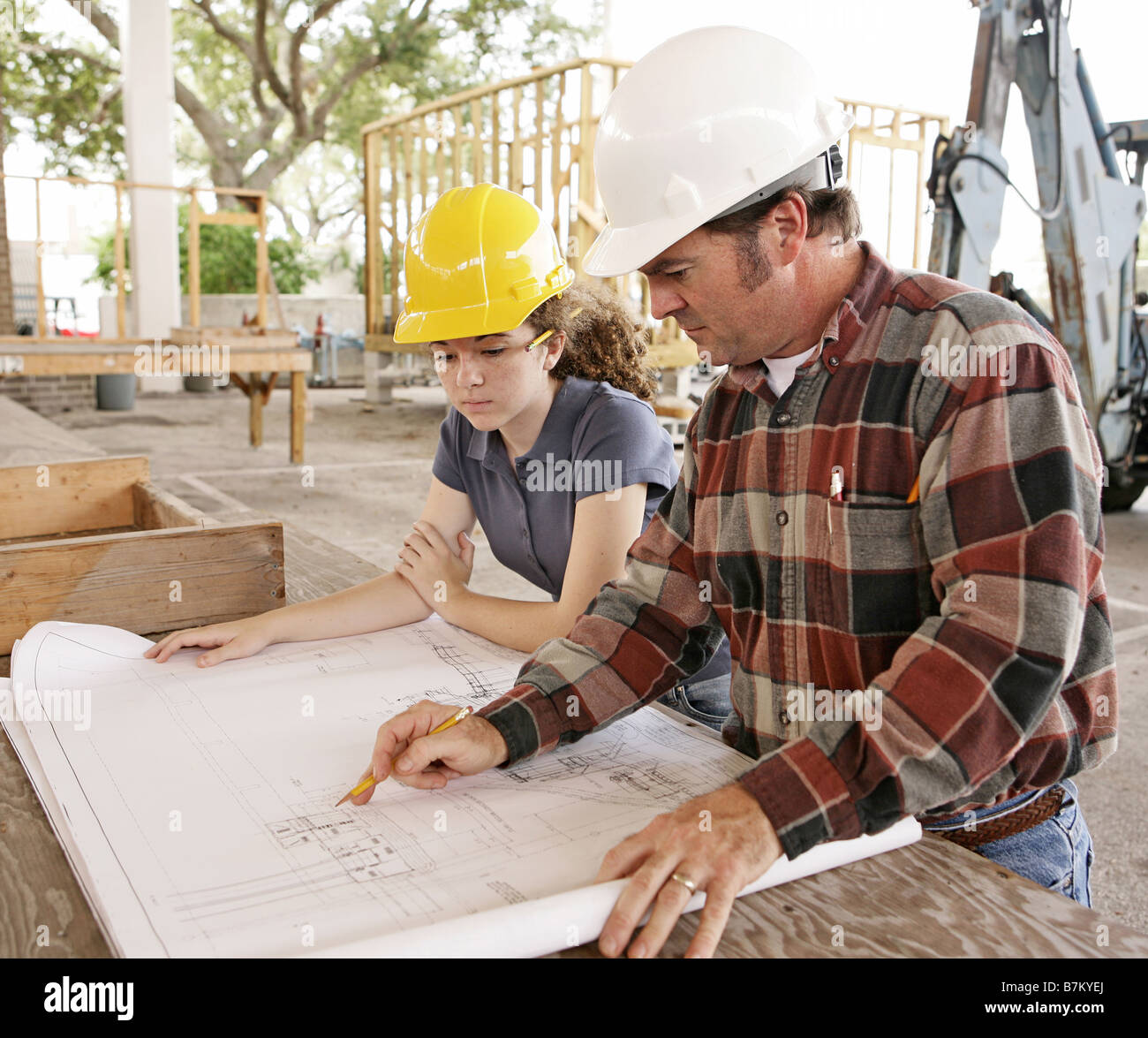 An engineer and a female student going over blueprints on a ...