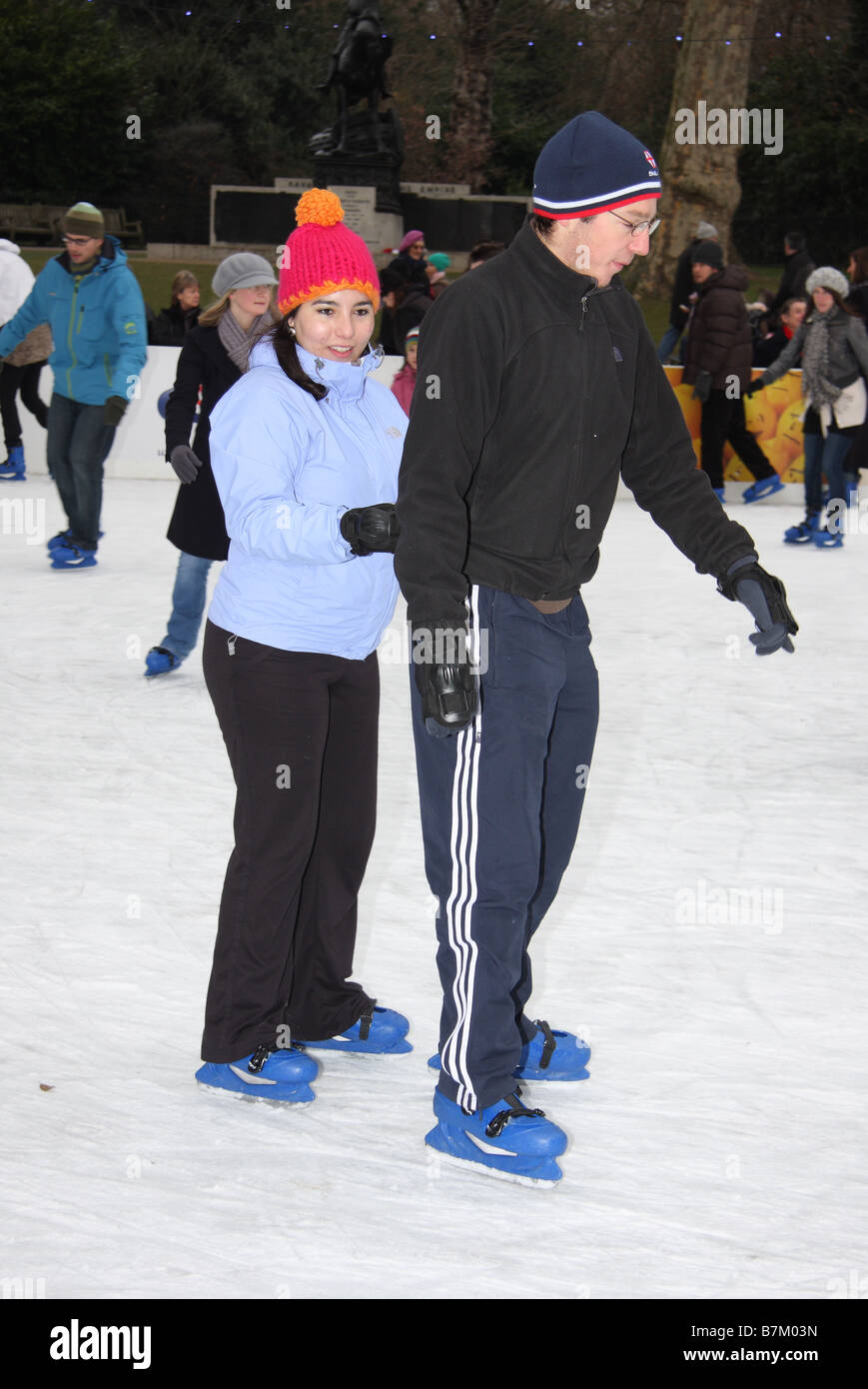 man couple woman ice skating skaters rink open air cold winter ...