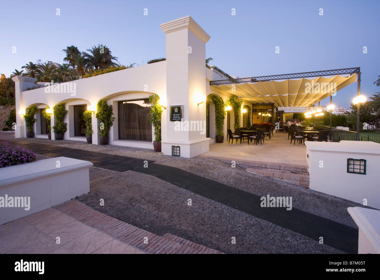 Club house with chairs and table on terrace below awning at golf course ...
