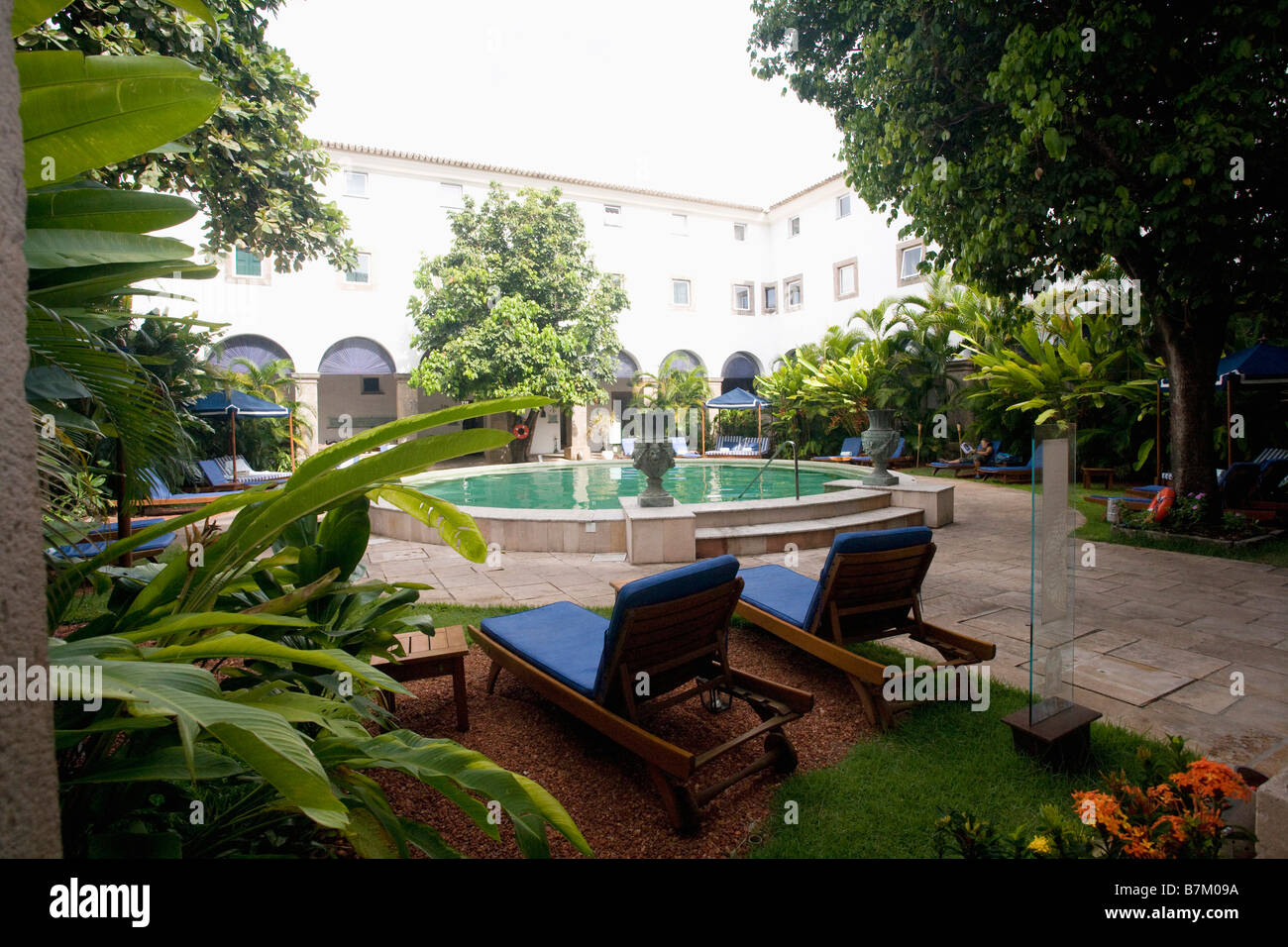 Loungers beside circular ornamental pool in lushly planted courtyard ...