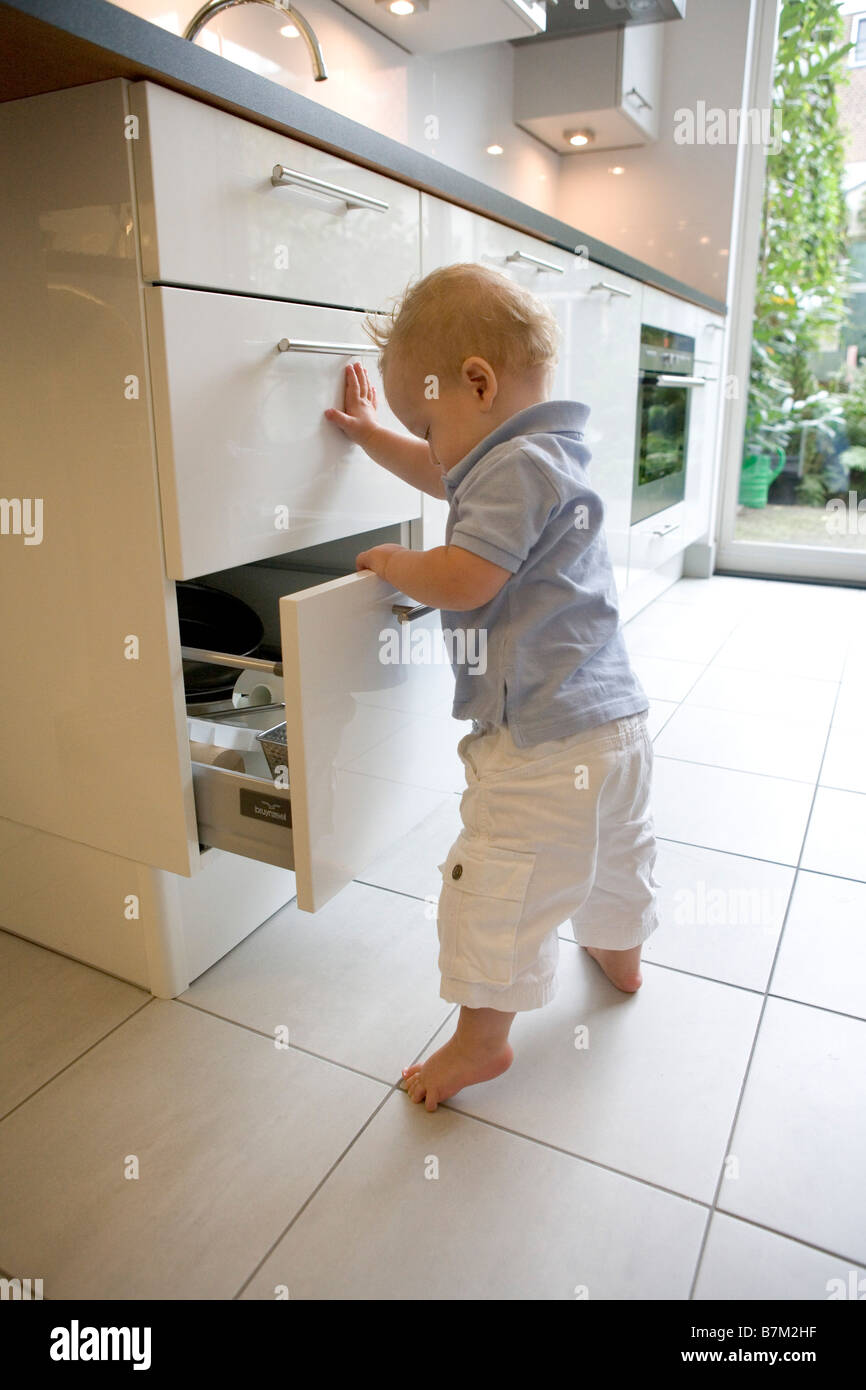 Toddlerboy opens a drawer in de kitchen Stock Photo - Alamy