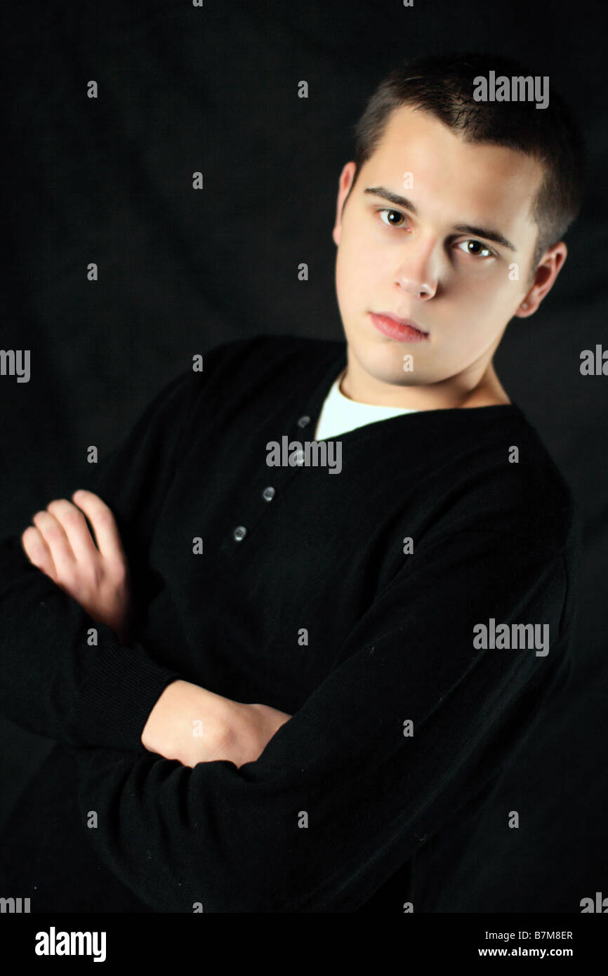 Young man on dark background with folded arms staring menacingly ...
