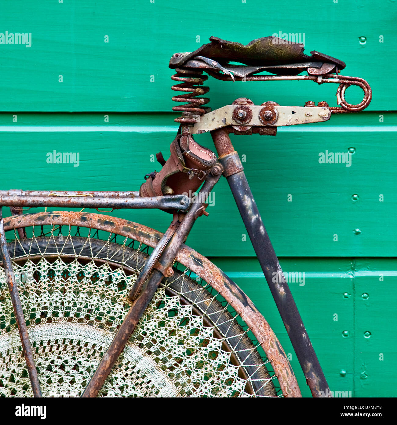 A rusty and worn old Dutch bicycle leaning against a bright green ...