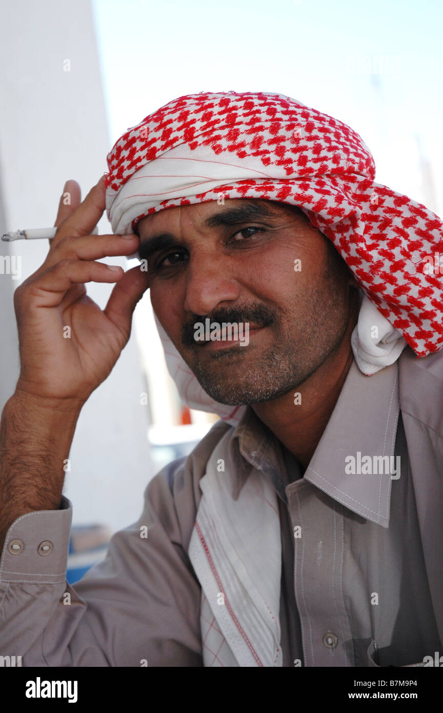 Local Omani man wearing a traditional headscarf poses with a cigarette ...