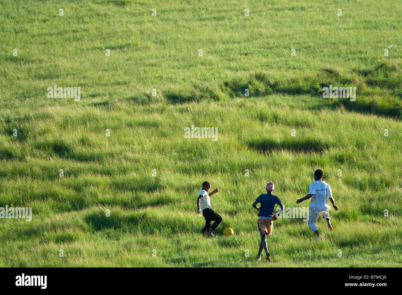 African boys play soccer in a field in a rural settlement in the ...