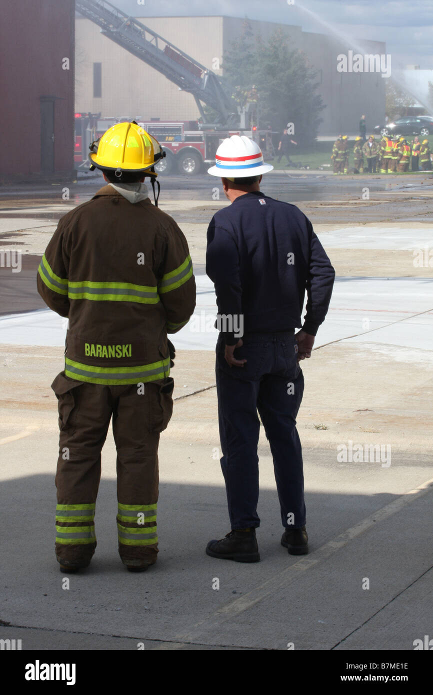 A firefighter and utility worker looking at a fire scene Stock Photo ...
