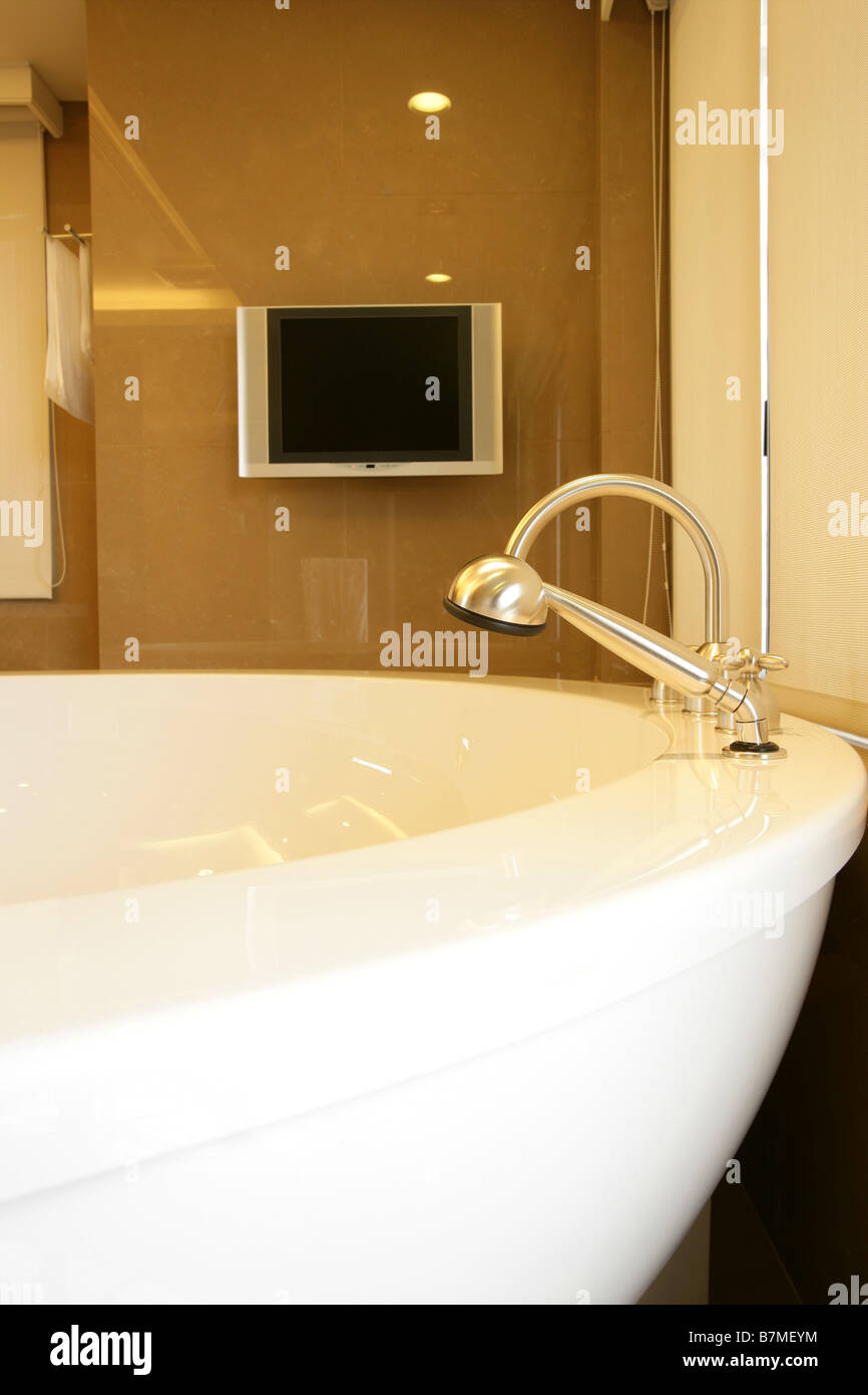 Close up of bathtub by window a flat screen television hanging on wall ...