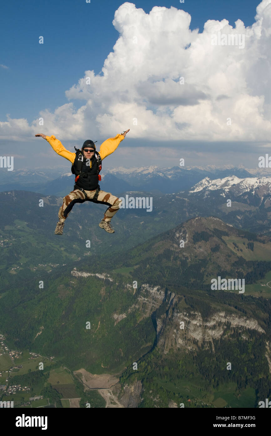 Skydiver is sit flying in between clouds and having a blast. He tries ...