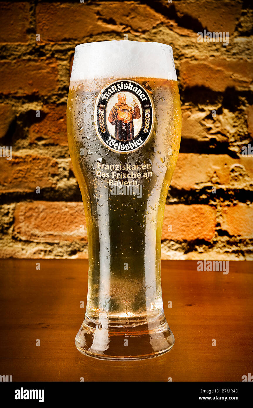 Glass of Franziskaner beer with water drops on a wooden table of pub ...